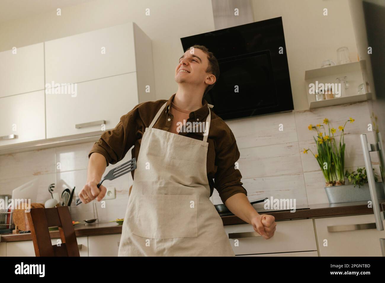 Happy man wearing apron dancing in kitchen at home Stock Photo - Alamy