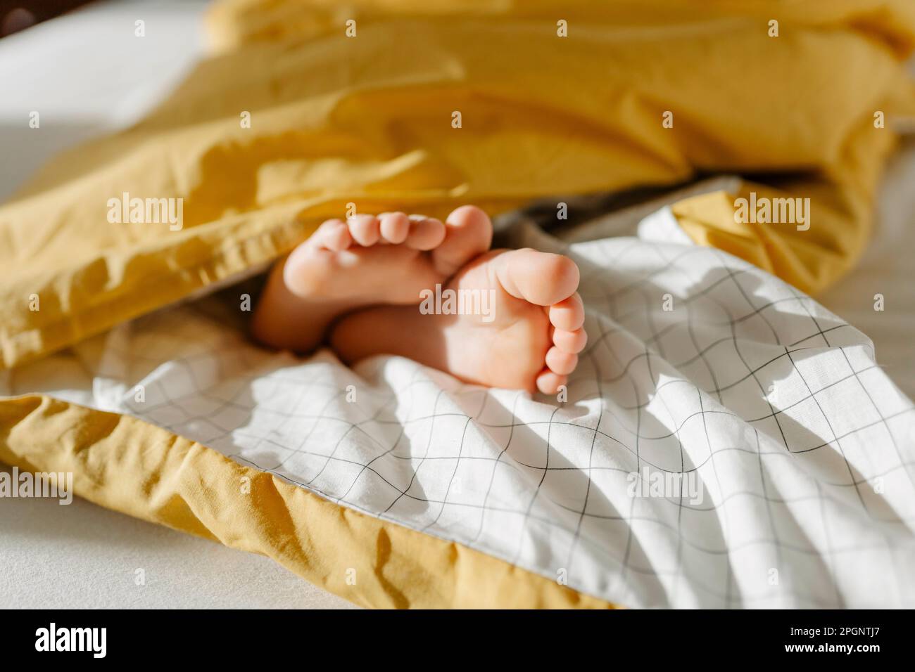 Feet of girl peeking out from blanket on bed Stock Photo - Alamy