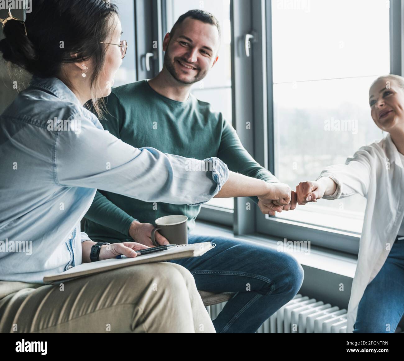 Happy business colleagues giving fist bump to each other at office ...