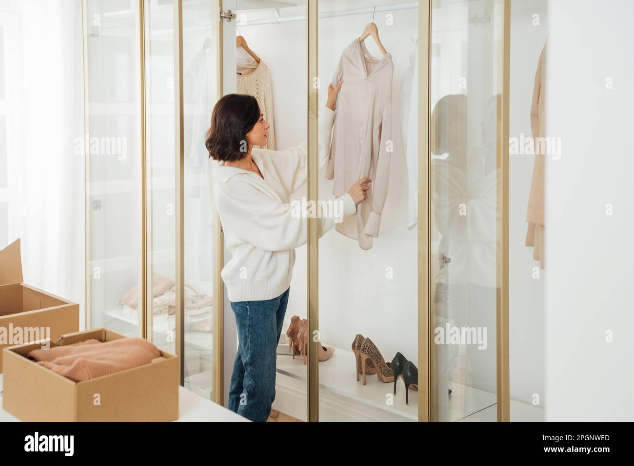 Young woman checking clothes hanging in closet at home Stock Photo - Alamy