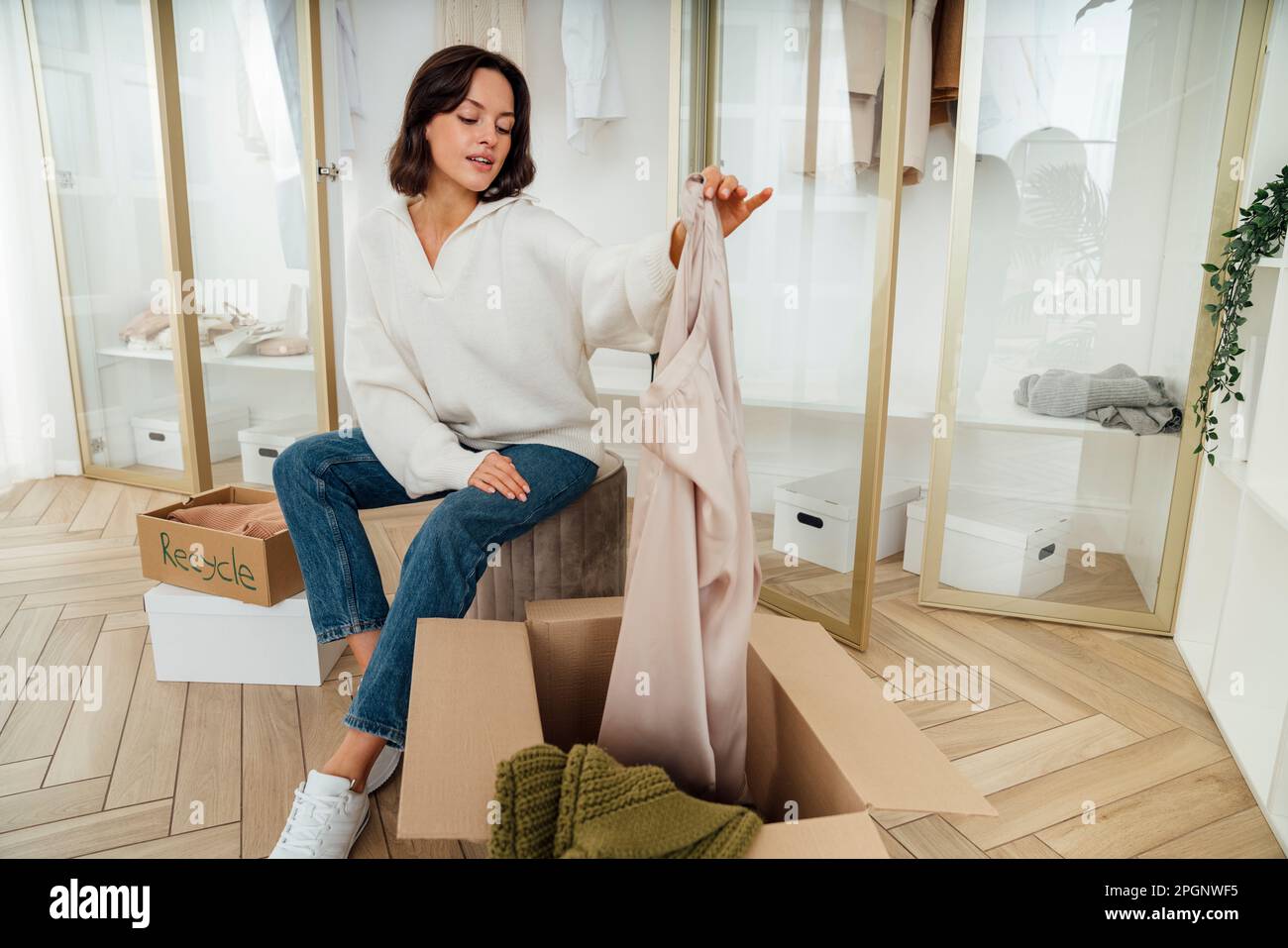 Young woman packing clothes in box to recycle at home Stock Photo - Alamy