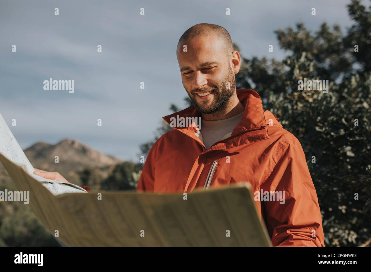 Smiling man reading map standing in nature Stock Photo - Alamy