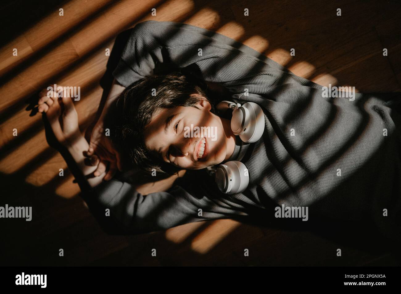 Blinds shadow on happy boy lying with wireless headphones Stock Photo ...