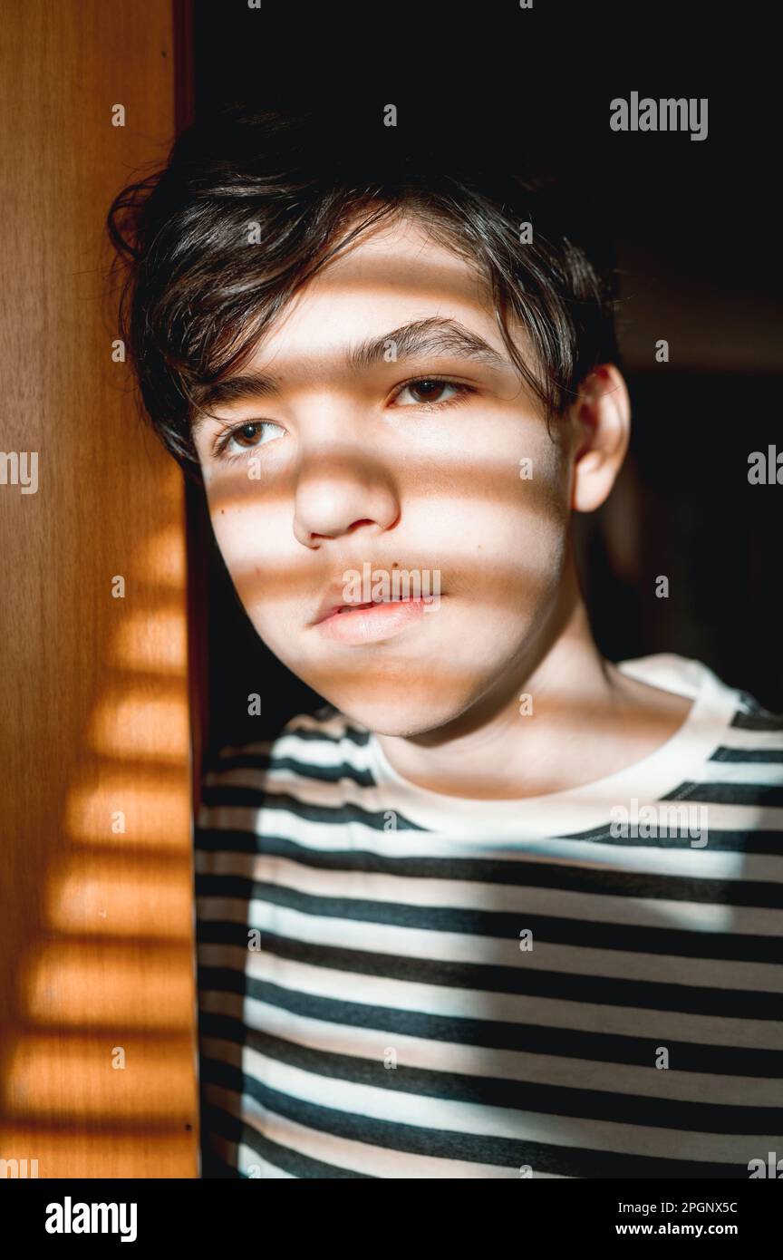 Thoughtful teenage boy with sunlight on face standing by door Stock ...