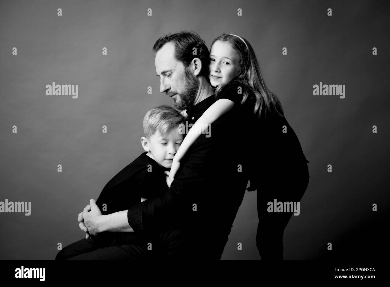 Man sitting with son on lap and daughter embracing from behind Stock ...