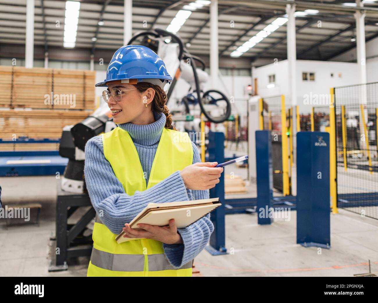Young engineer with note pad and pen pointing in factory Stock Photo ...