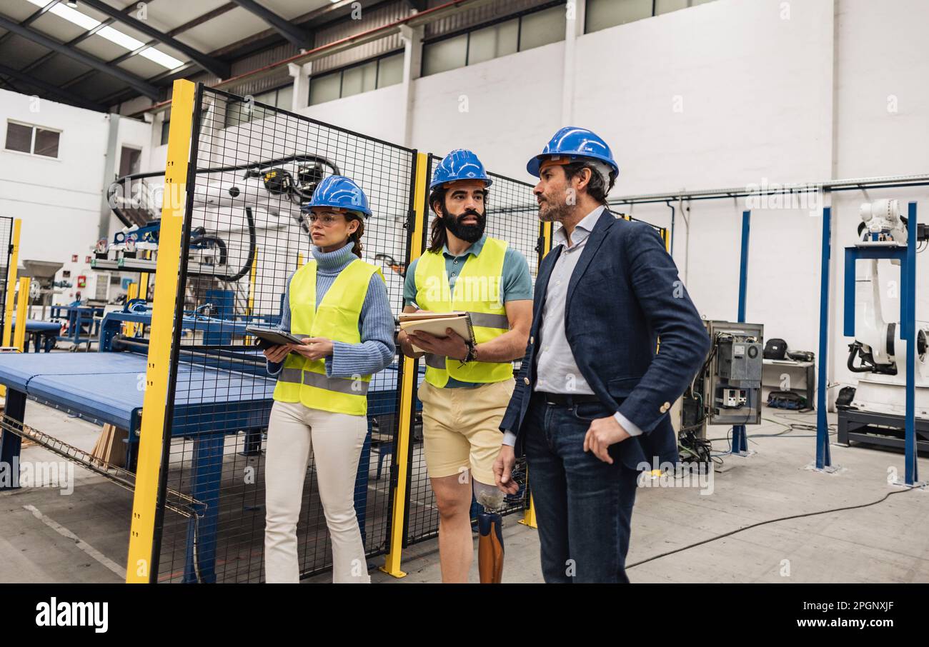 Engineer working with colleagues in factory Stock Photo - Alamy