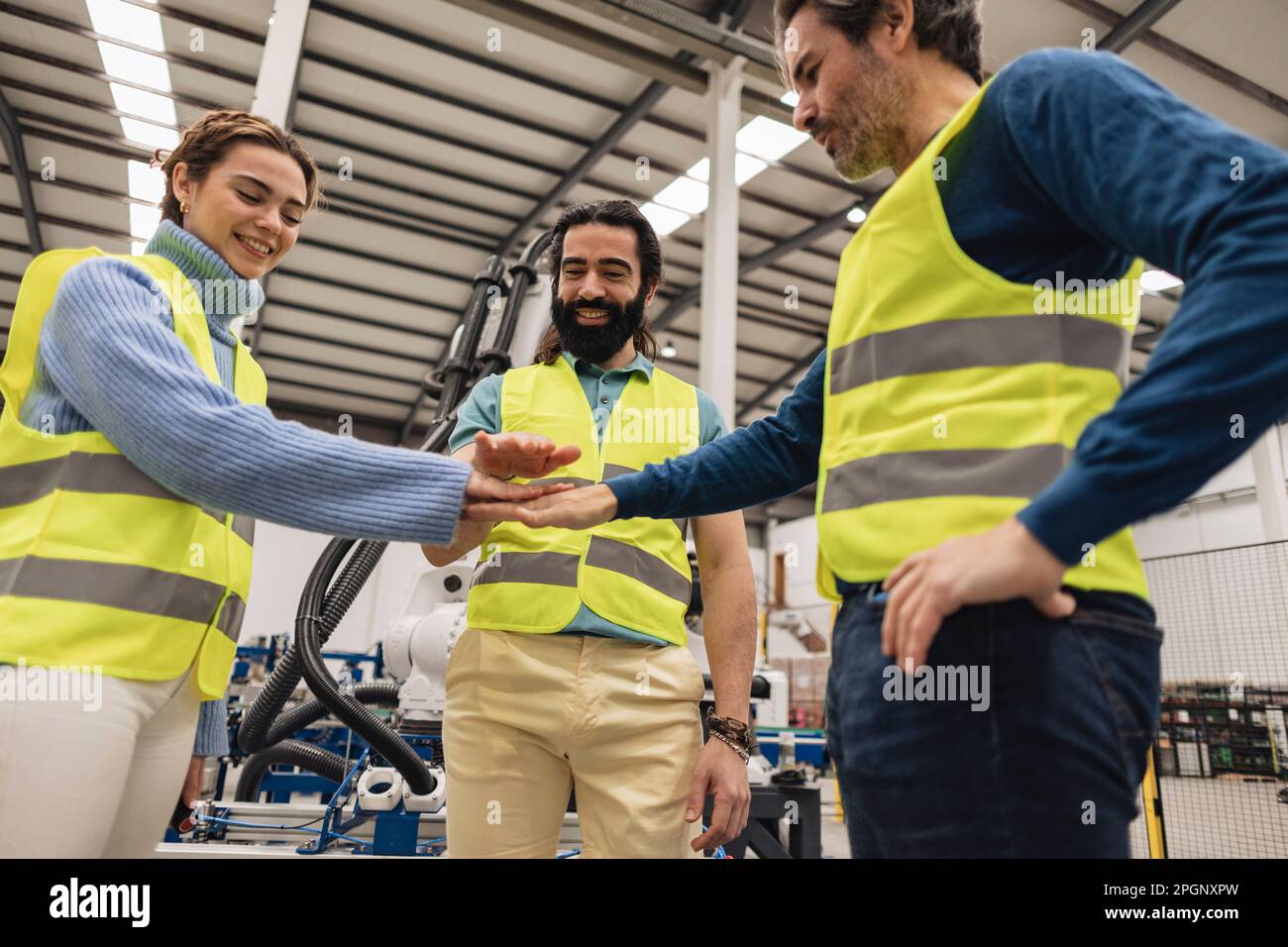 Happy engineers stacking hands in factory Stock Photo - Alamy