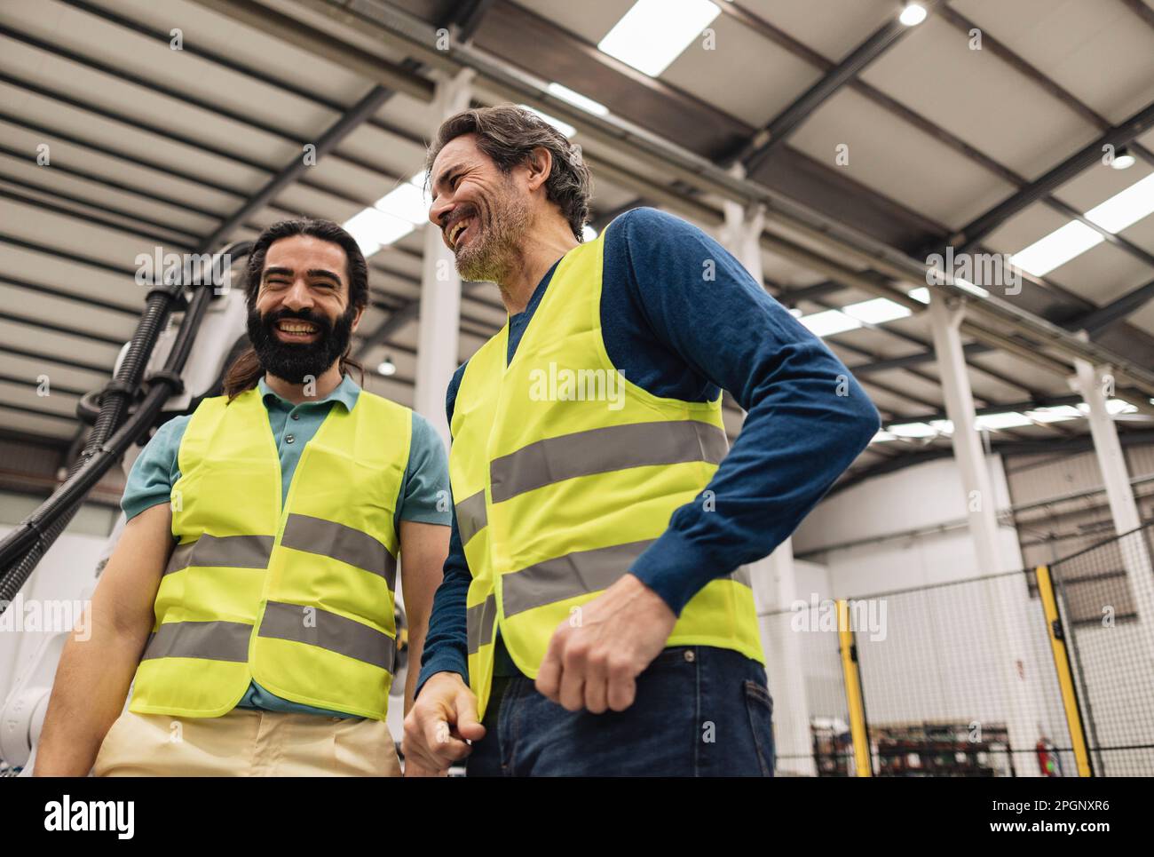 Happy engineers wearing reflective clothing standing in robotics ...