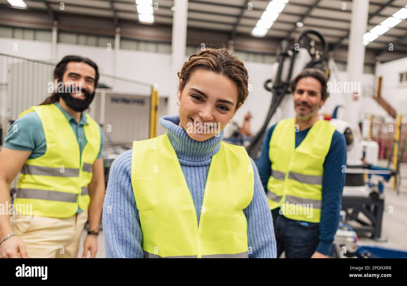 Happy engineers wearing reflective clothing standing with in robotics ...