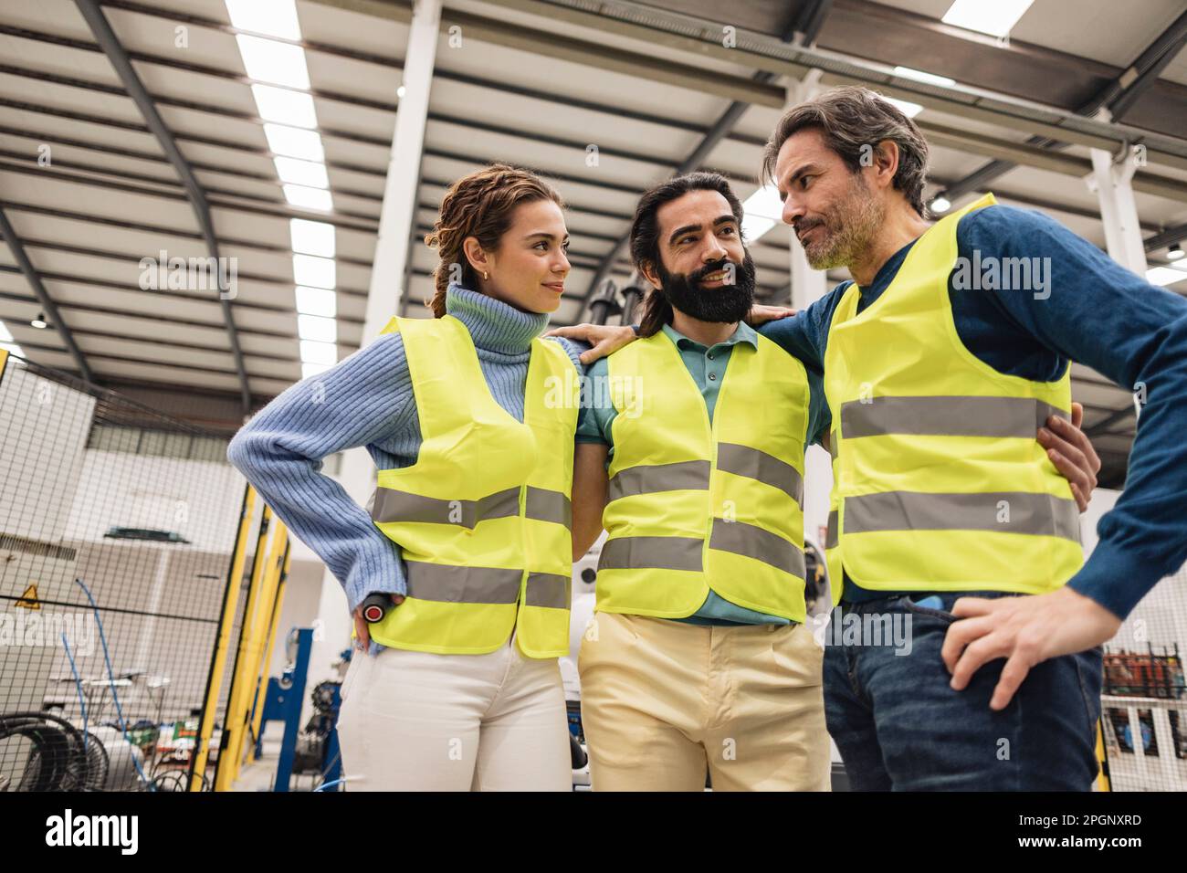 Happy engineers wearing reflective clothing standing with arm around in ...