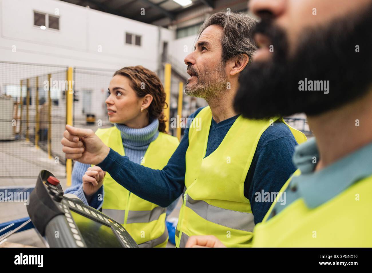 Engineer holding control panel working with colleagues in factory Stock ...