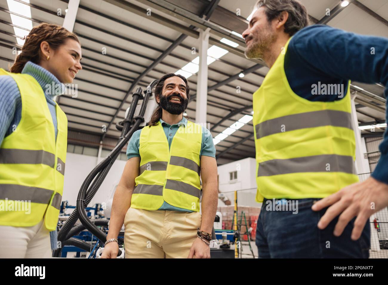Happy engineers wearing reflective clothing talking with each other in ...