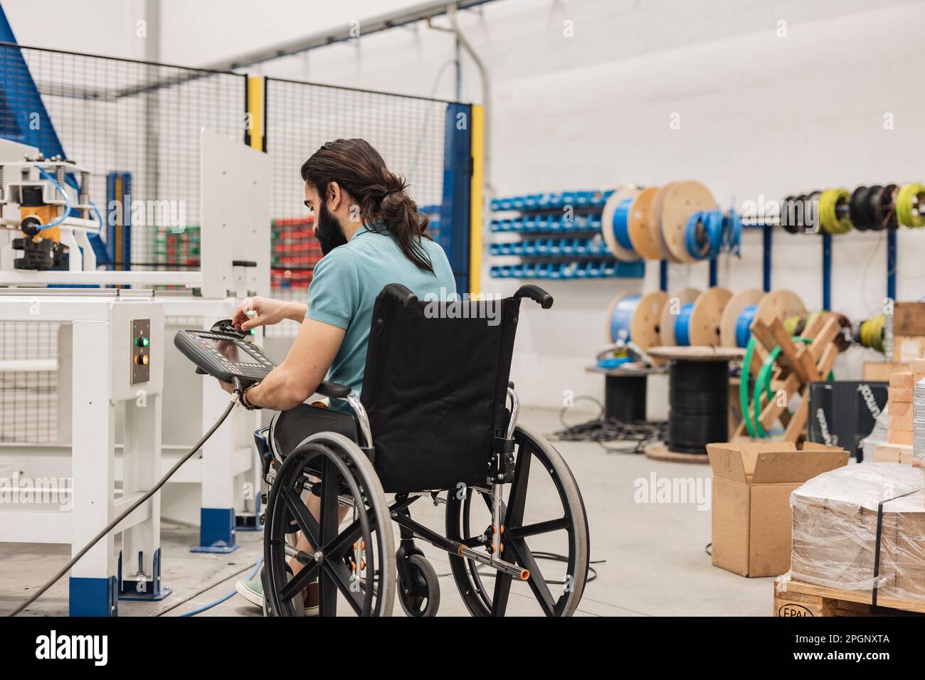 Engineer sitting in wheelchair using control panel at factory Stock ...