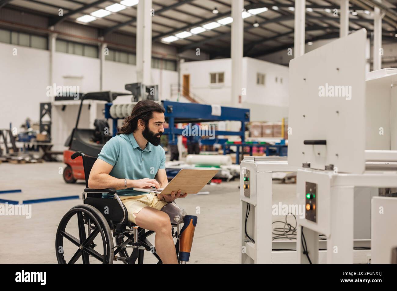 Engineer sitting in wheelchair analyzing machine through laptop in ...
