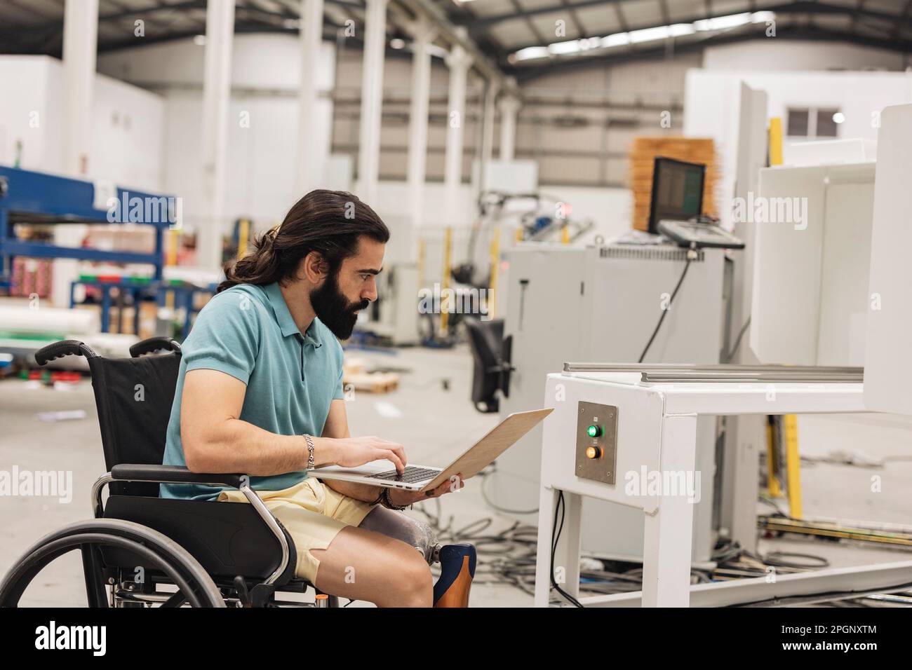 Engineer sitting in wheelchair examining machine through laptop in ...