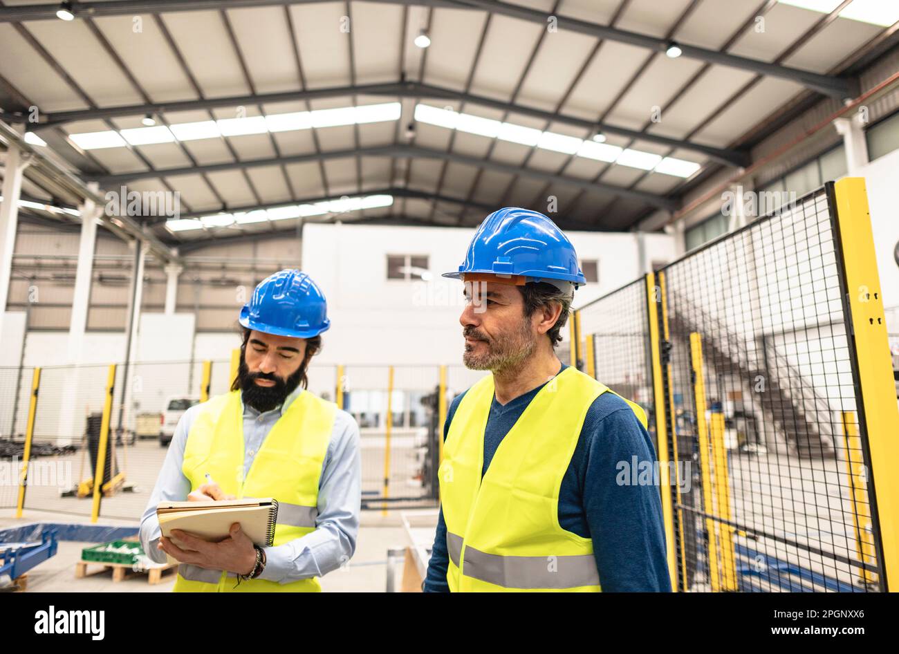 Engineer with colleague writing notes in robotics factory Stock Photo ...