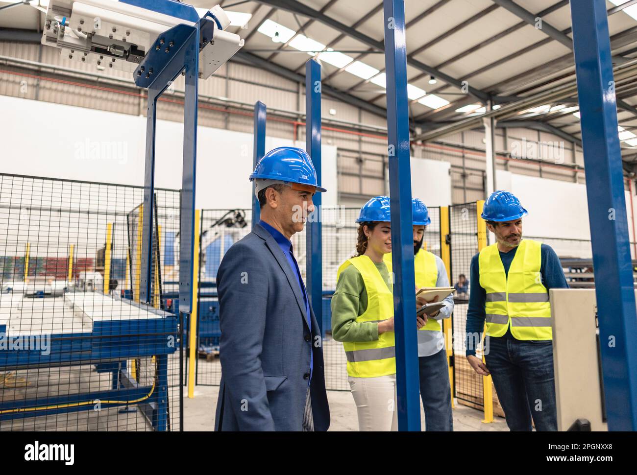 Engineer wearing hardhat with colleagues in factory Stock Photo - Alamy