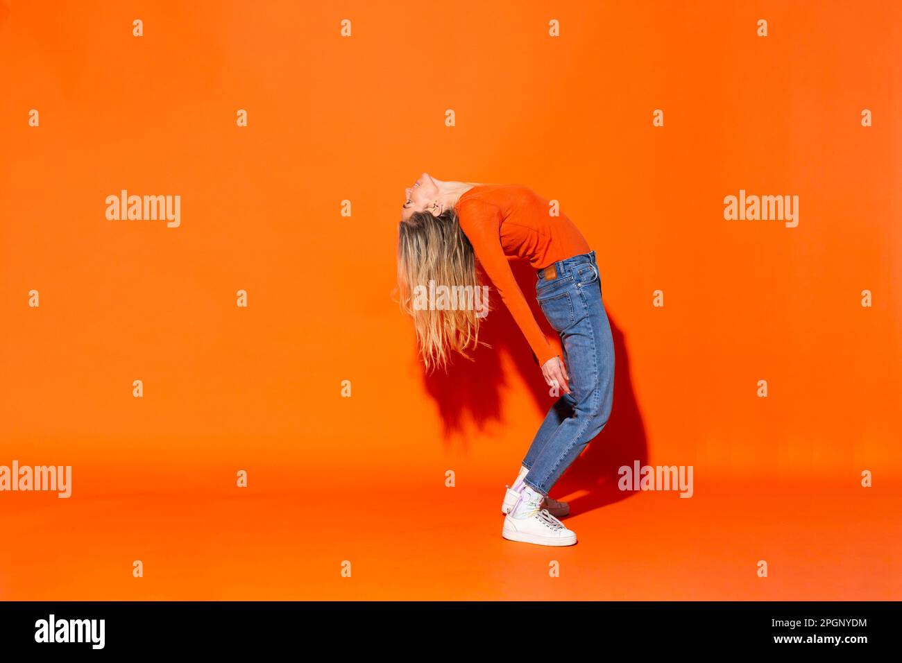 Woman bending over backwards against orange background Stock Photo - Alamy