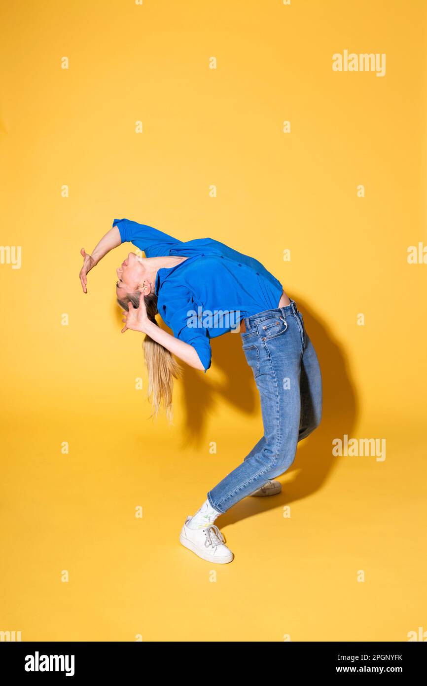 Woman bending over backwards against yellow background Stock Photo - Alamy