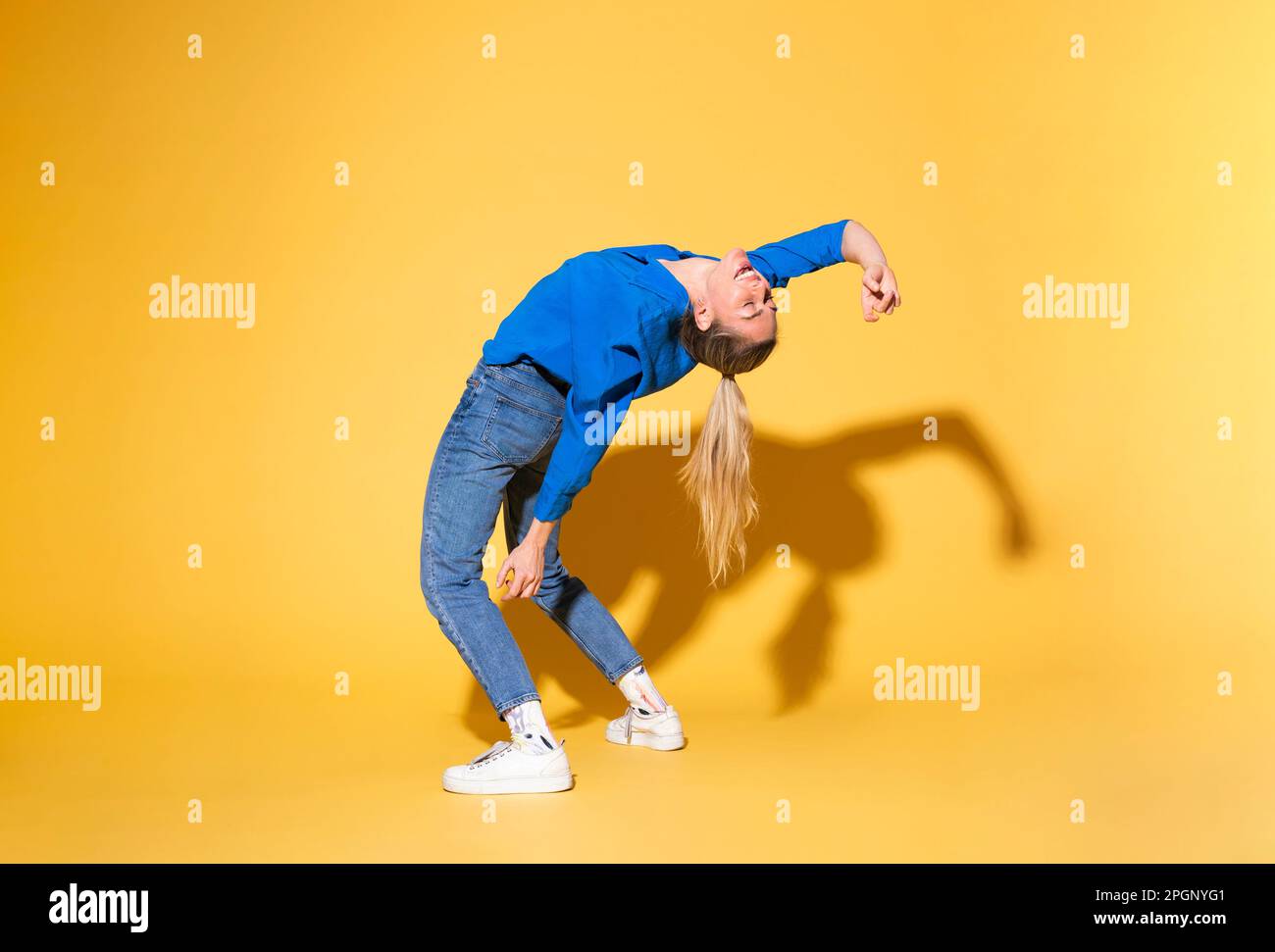 Carefree woman bending backwards against yellow background Stock Photo ...