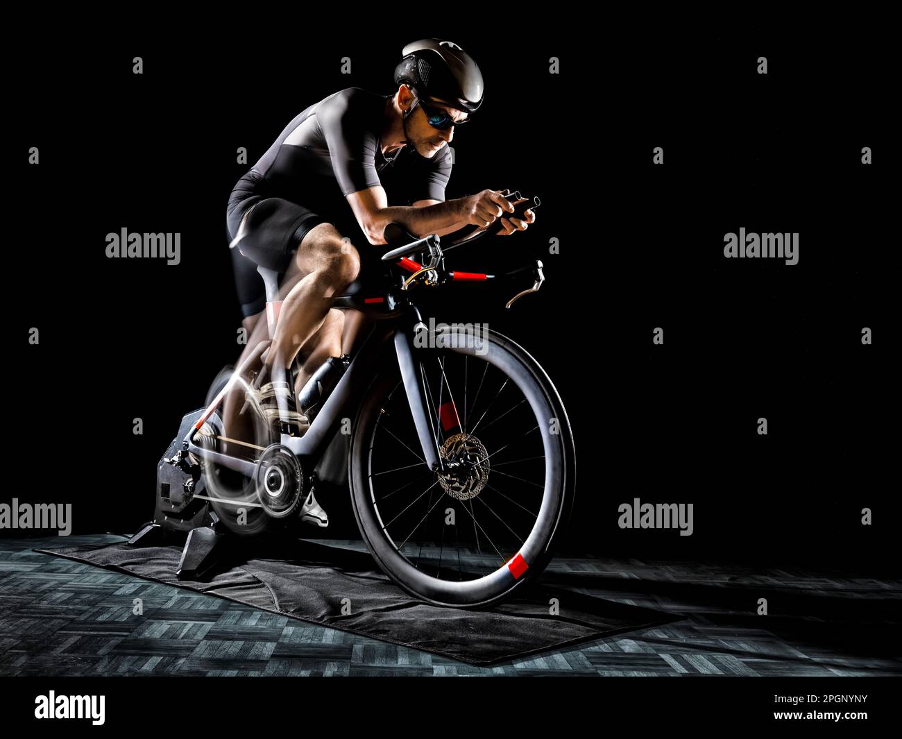 Determined athlete sitting on turbo dinner against black background ...