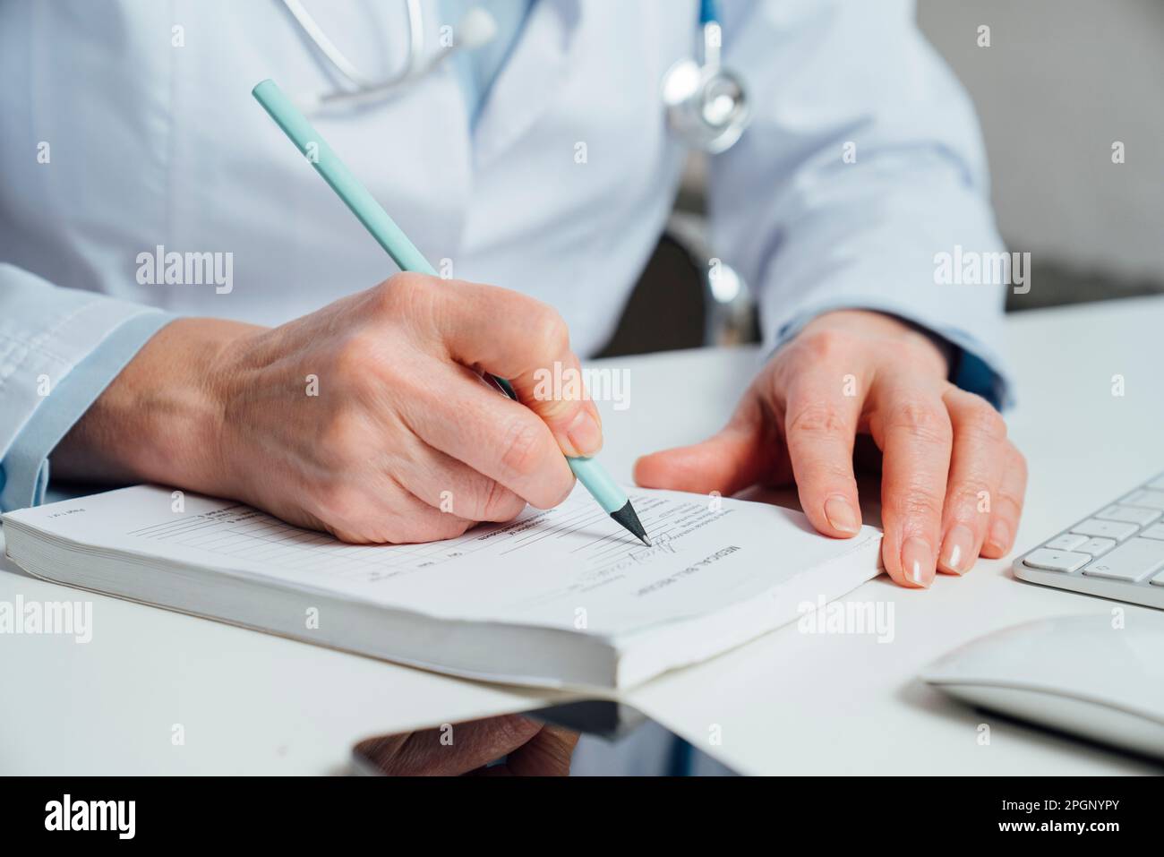 Doctor writing prescription with pen at desk Stock Photo - Alamy