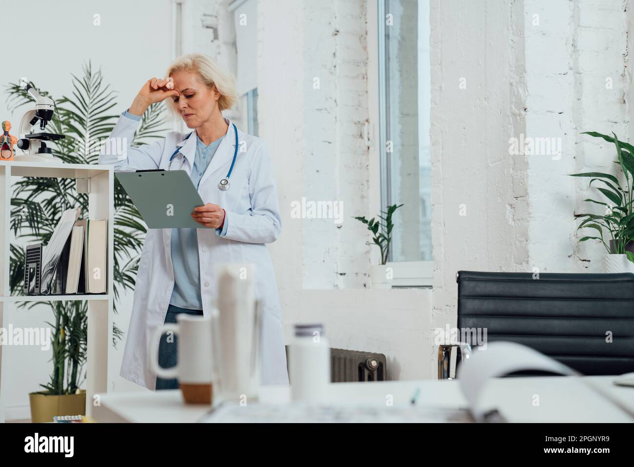 Doctor examining document leaning on shelf at clinic Stock Photo - Alamy
