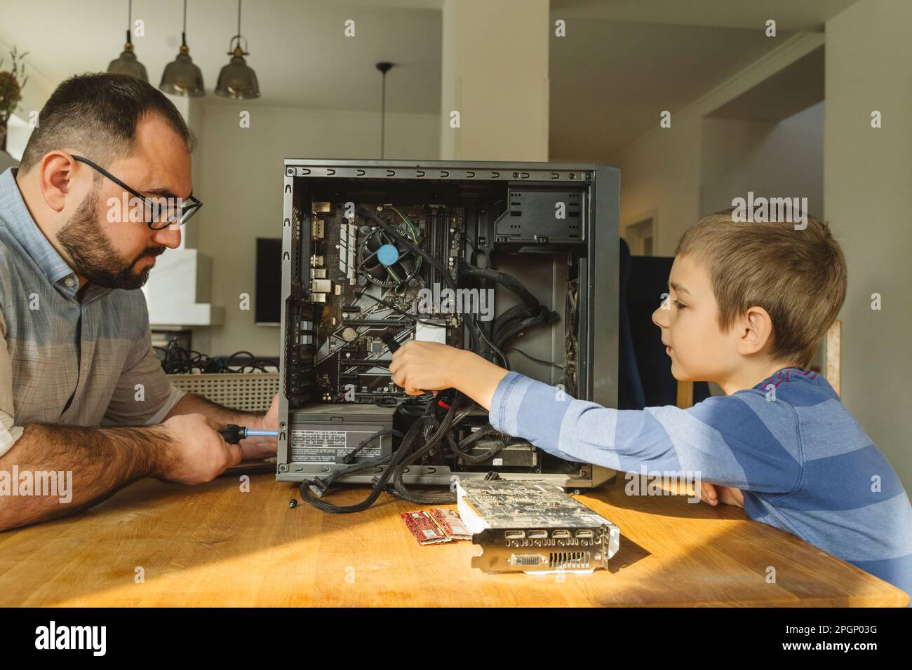 Son helping father repairing computer at home Stock Photo - Alamy