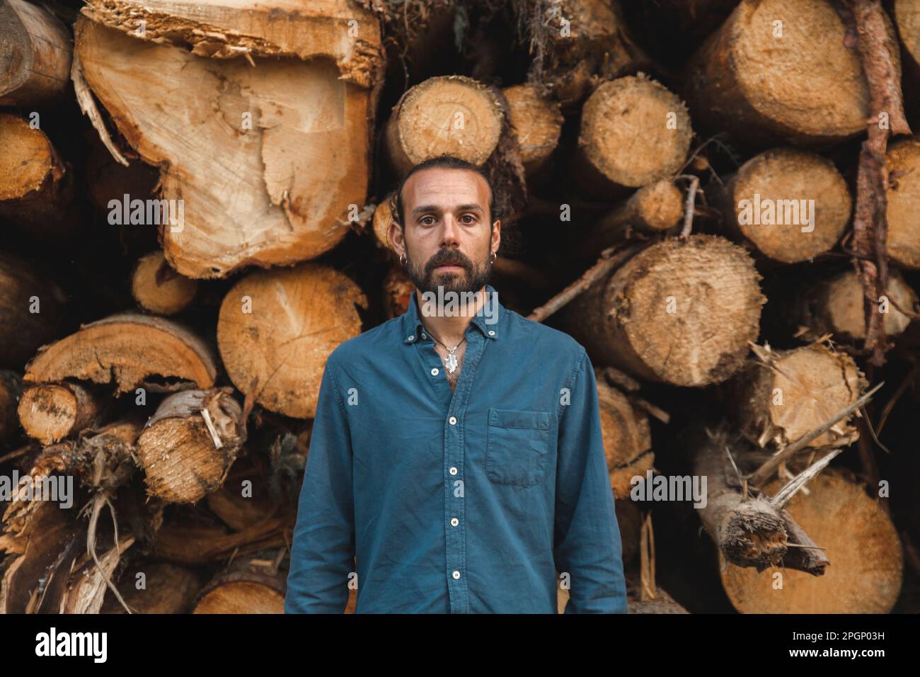 Man standing in front of logs at sawmill Stock Photo - Alamy