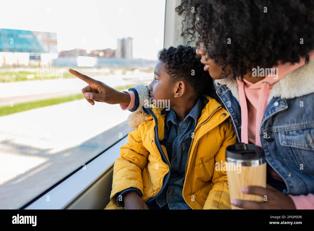 Mother sitting with son pointing through window in train Stock Photo ...
