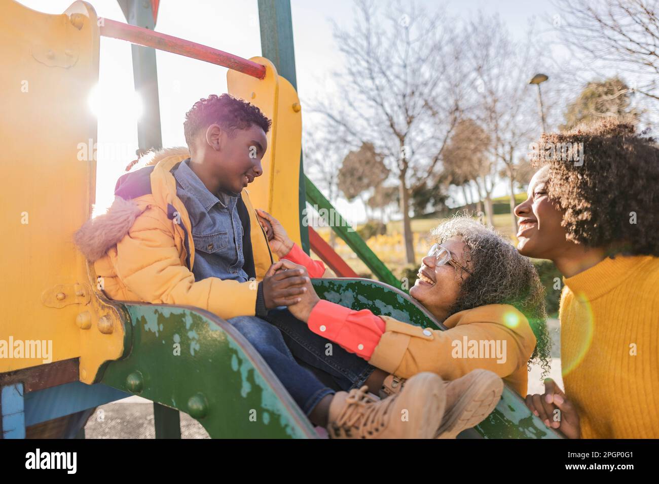 Boy having fun with family on slide on playground Stock Photo - Alamy