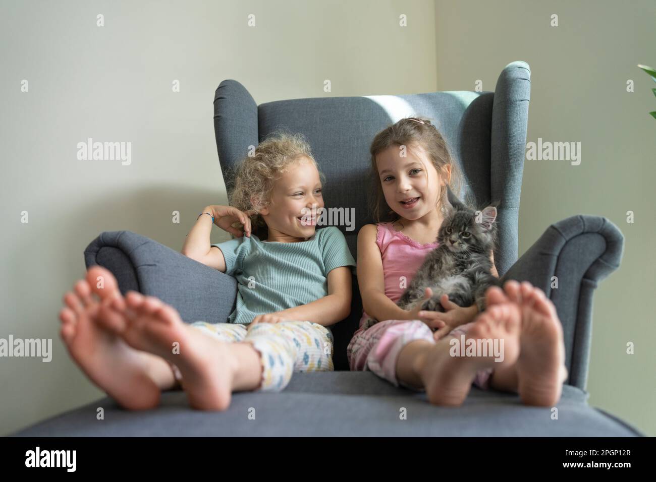 Smiling friends sitting together in armchair at home Stock Photo - Alamy