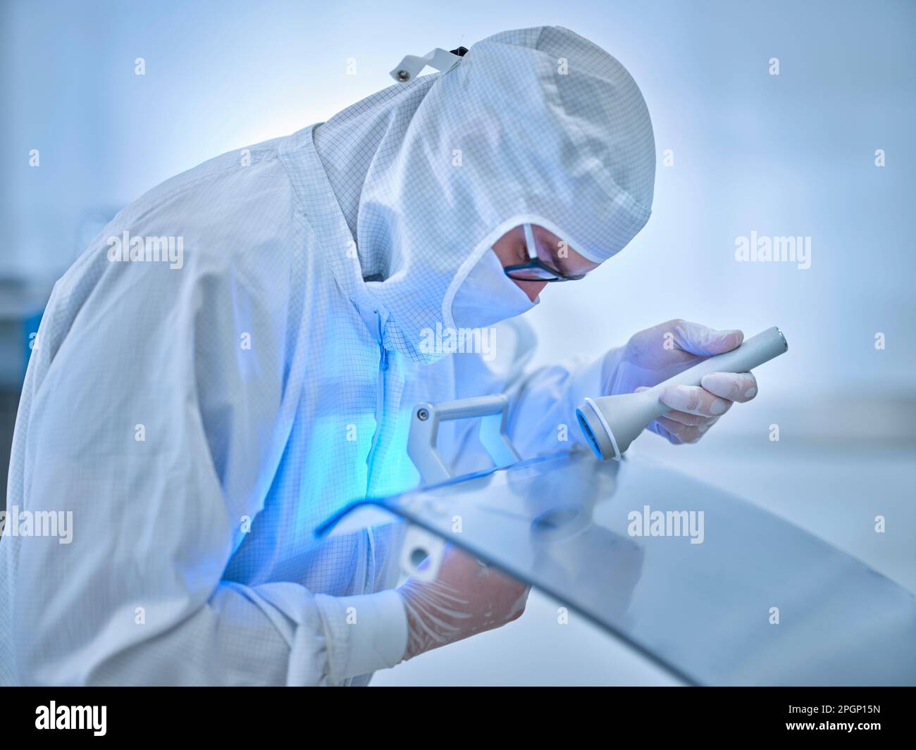 Technician examining surface for dirt with blue light in laboratory ...