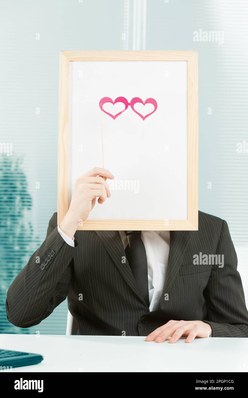 Man with framed sign head in an office. In front of the fake head made ...