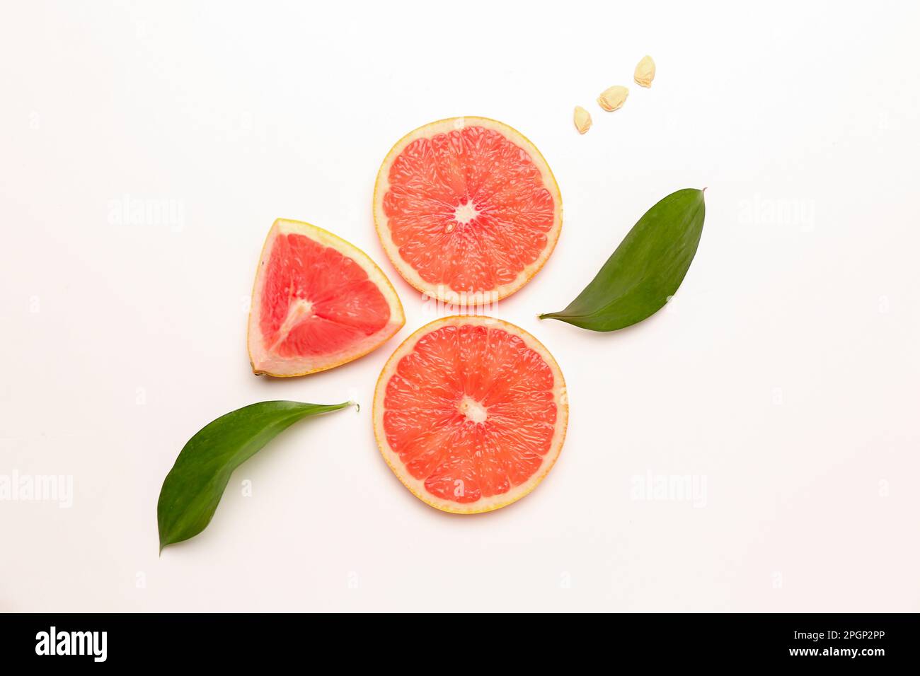 Composition with pieces of ripe grapefruit, seeds and plant leaves ...