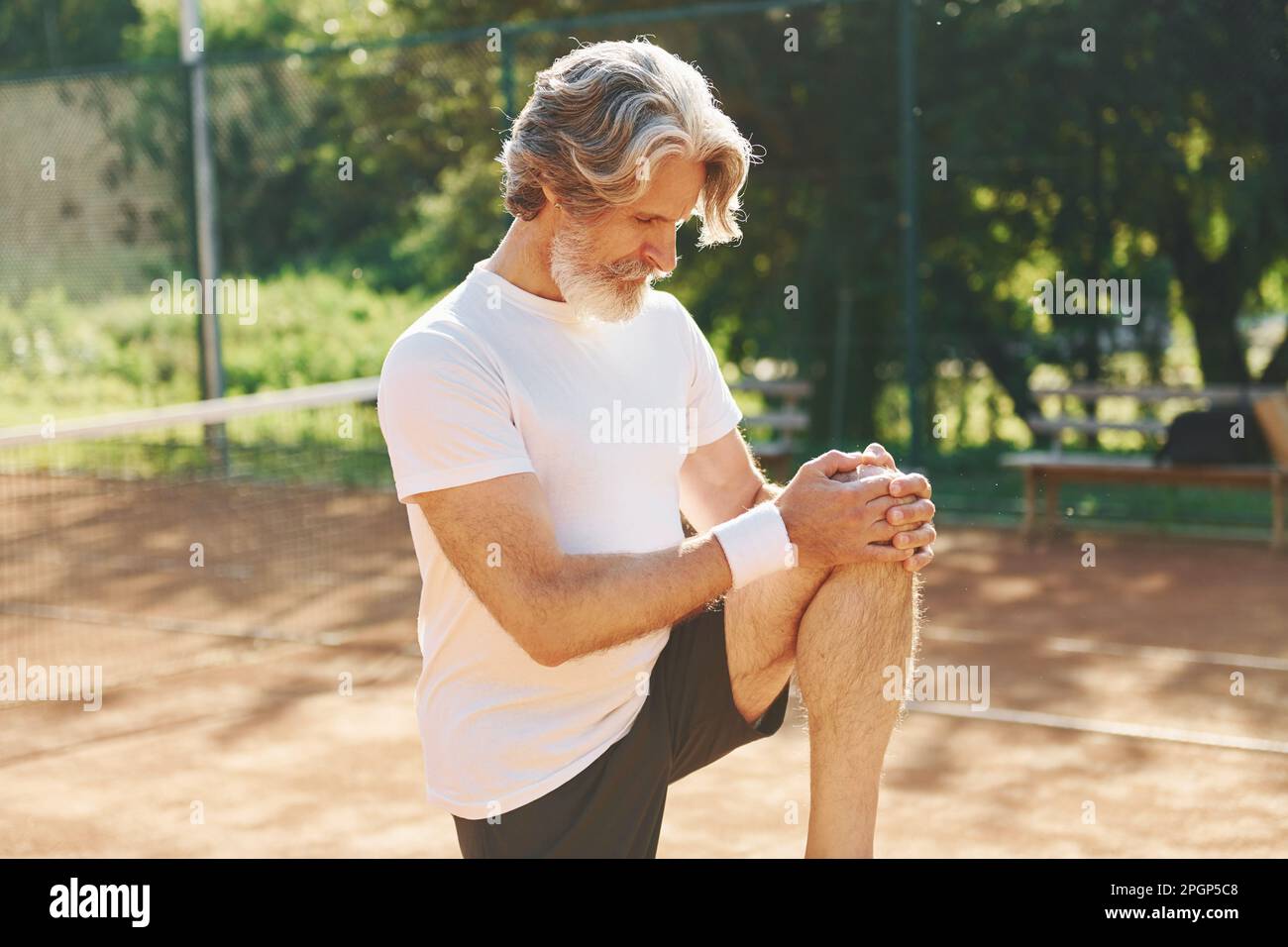 Doing warm up exercises. Senior modern stylish man outdoors on the ...