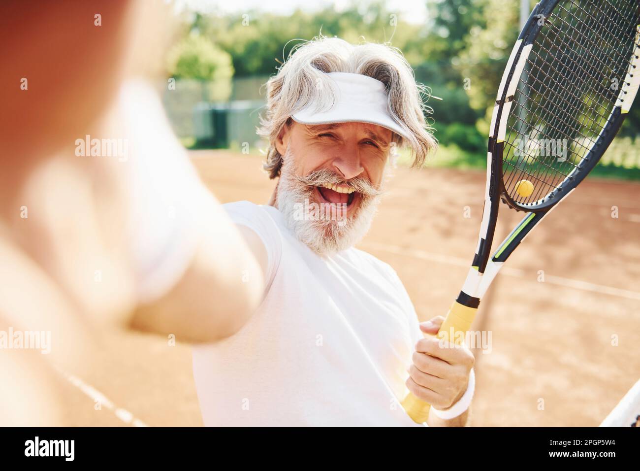Senior modern stylish man with racket outdoors on tennis court at ...