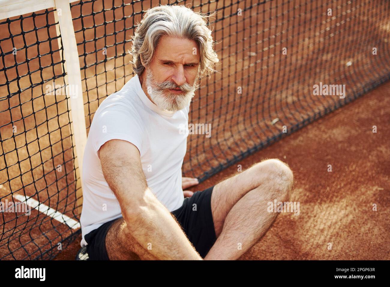 Sits on the ground and takes break. Senior modern stylish man with ...