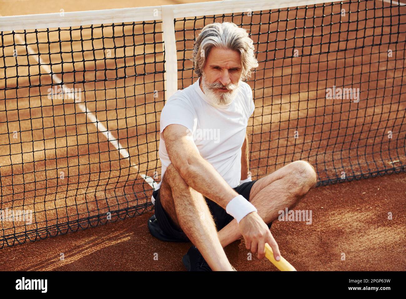 Sits on the ground and takes break. Senior modern stylish man with ...