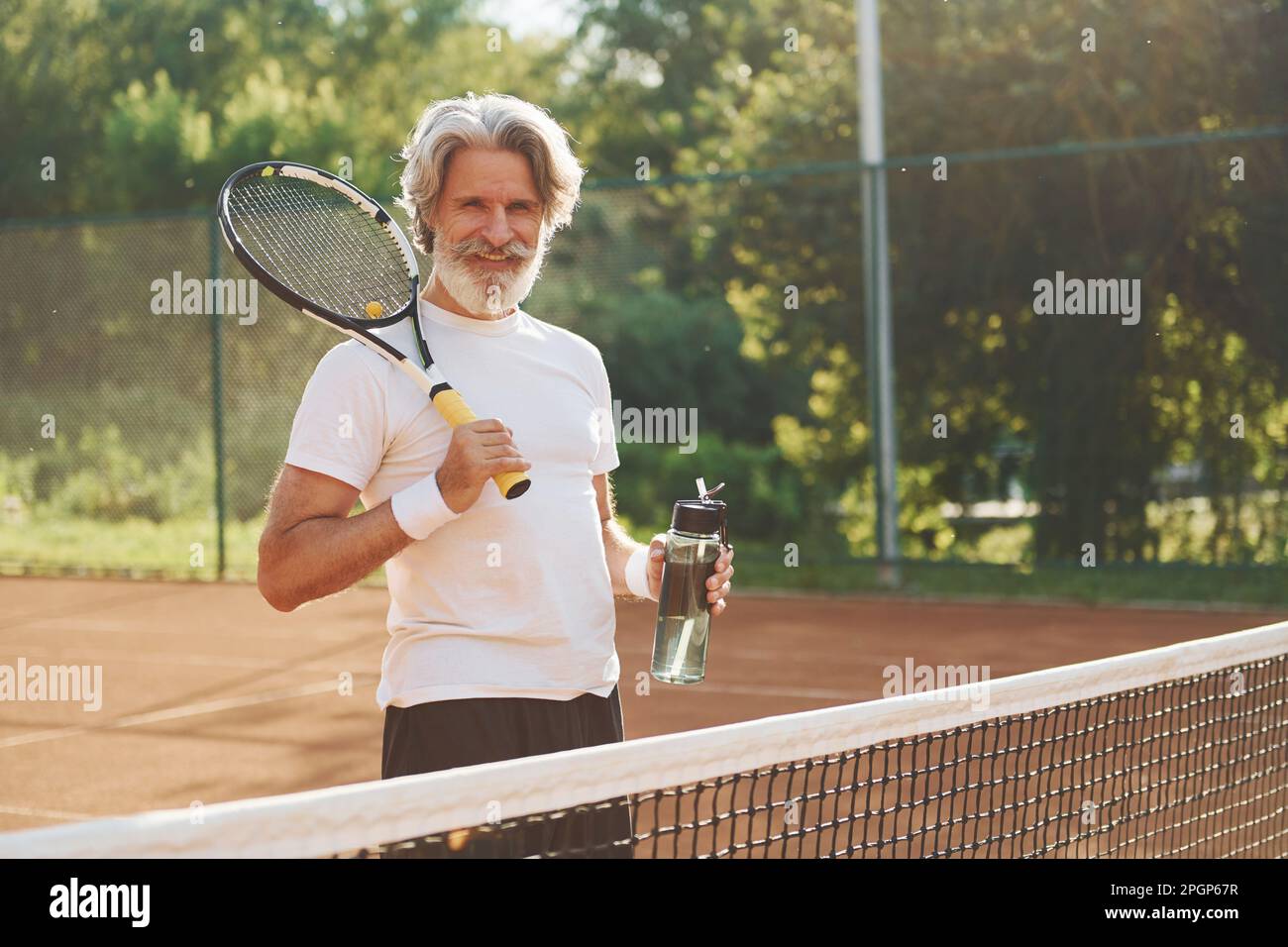 Holding racket. Senior modern stylish man with racket outdoors on ...