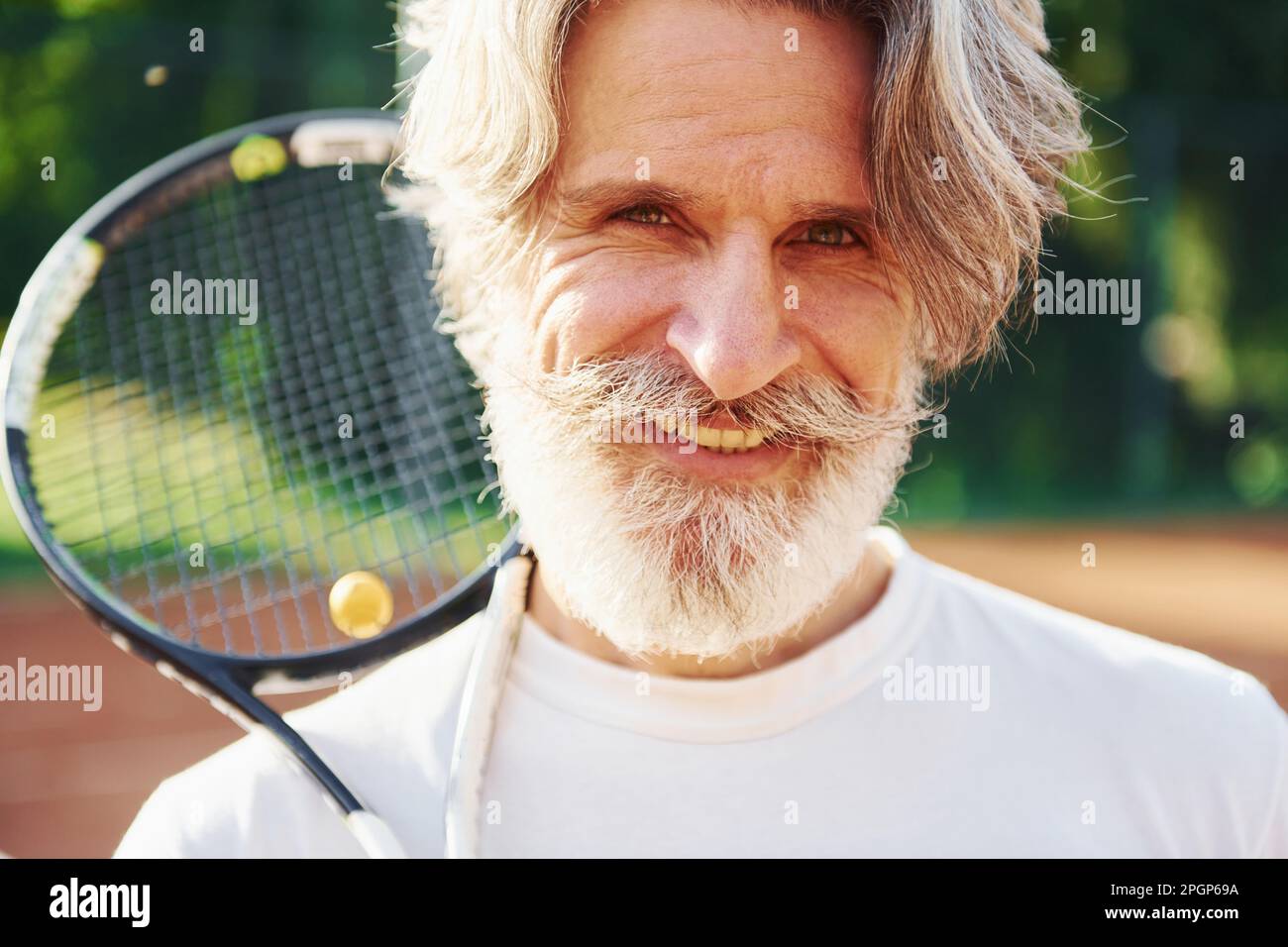 Holding racket. Senior modern stylish man with racket outdoors on ...