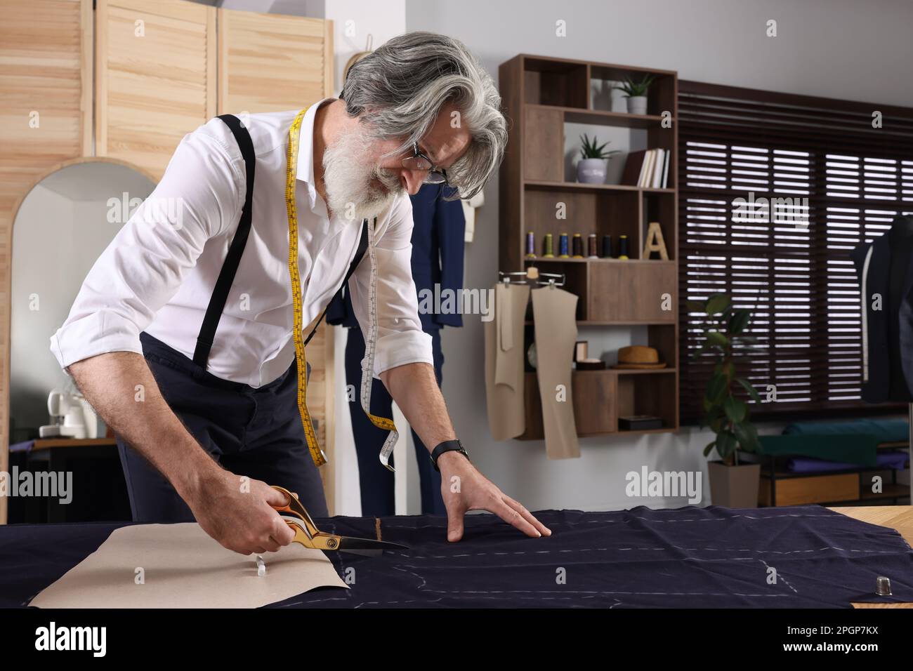 Professional tailor cutting fabric by following chalked sewing pattern ...