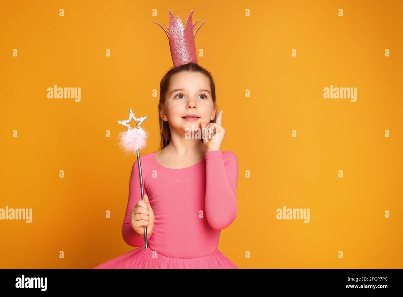 Cute girl in pink crown with magic wand on yellow background, space for ...