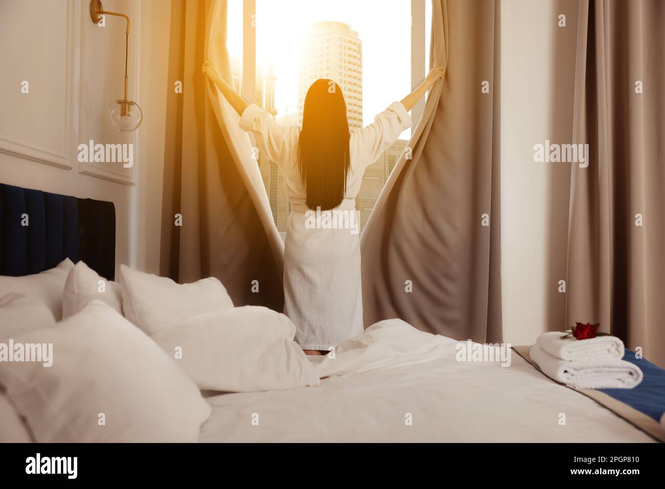 Young woman opening window curtains in hotel room, back view Stock ...