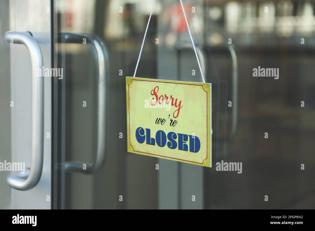 Yellow sign with text Sorry we're Closed hanging on glass door ...