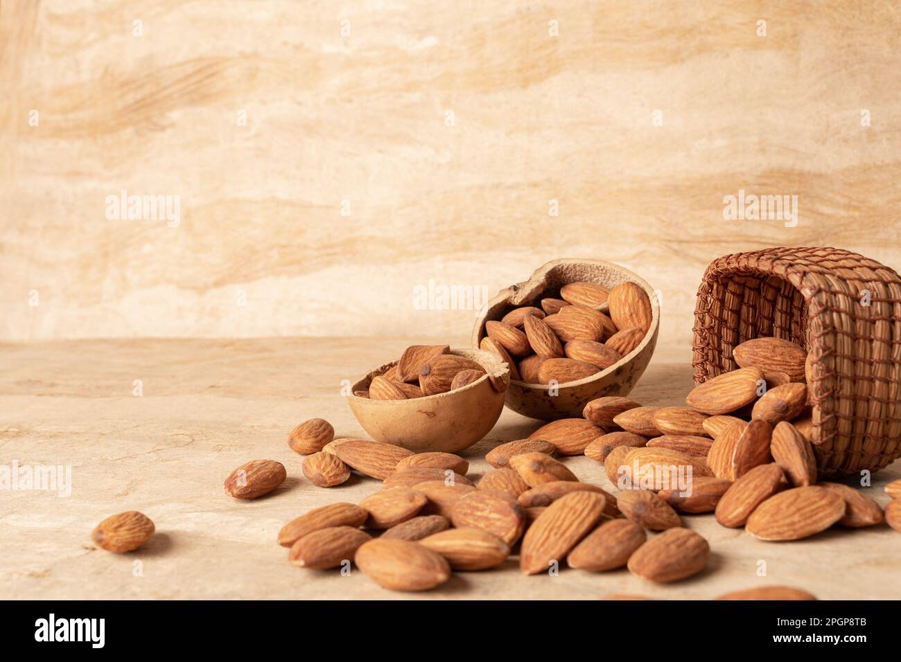 Shelled almonds in rustic containers. Amate paper background. Copy ...