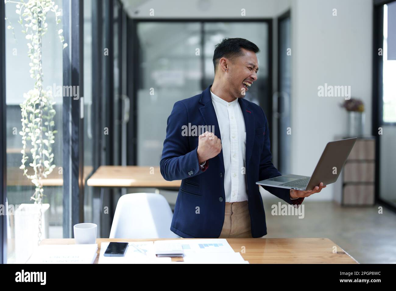 Portrait of an Asian male business owner standing with a computer ...