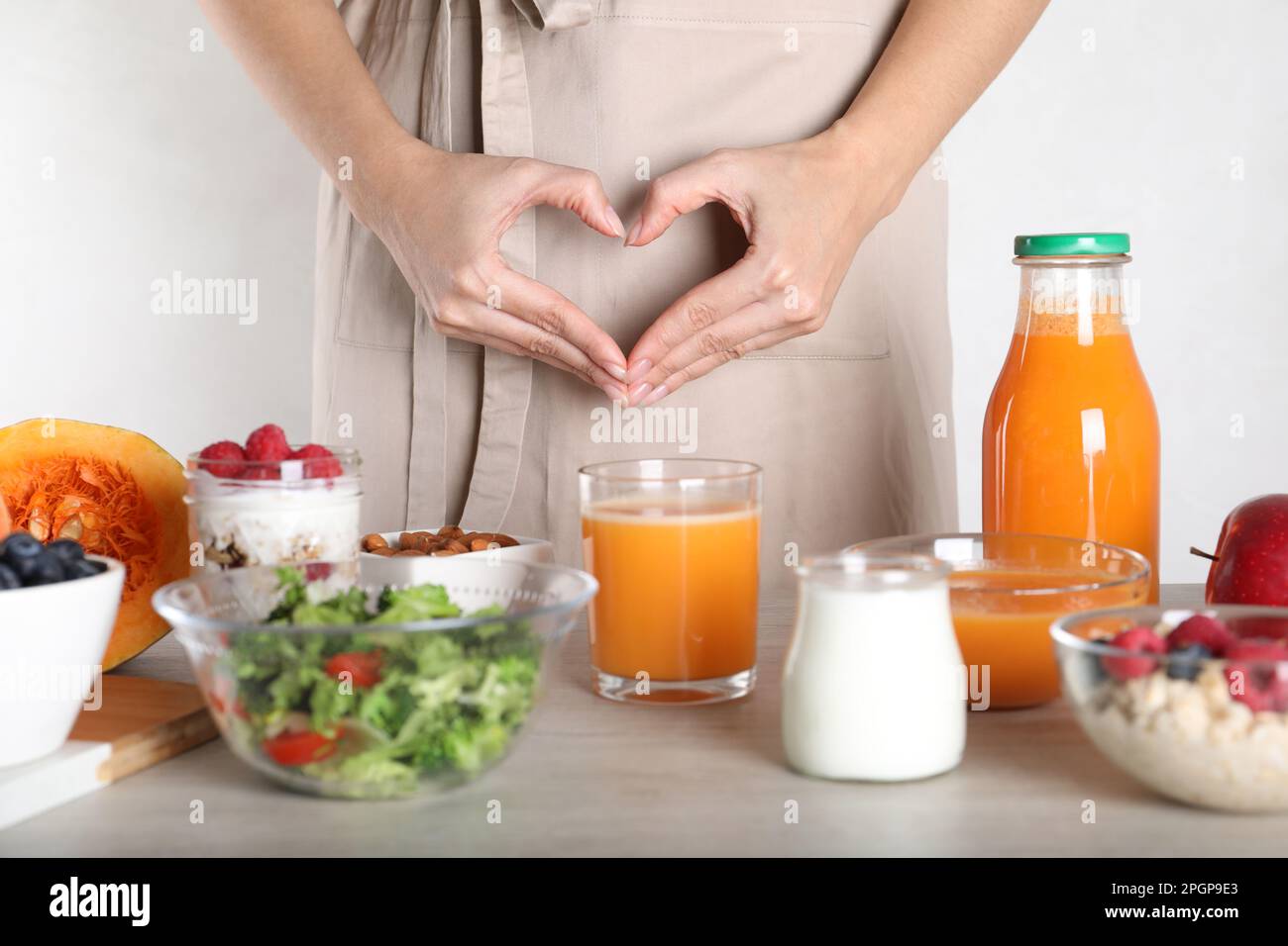Woman making heart near table with food, closeup. Balanced nutrition ...