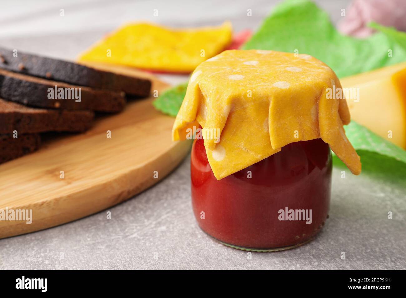 Jar of tomato paste covered with beeswax food wrap on light grey table ...